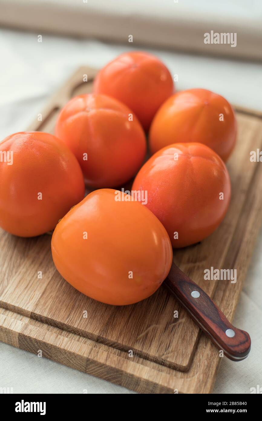 Big ripe persimmon fruits, winter fruit, cut on wooden board and black ...