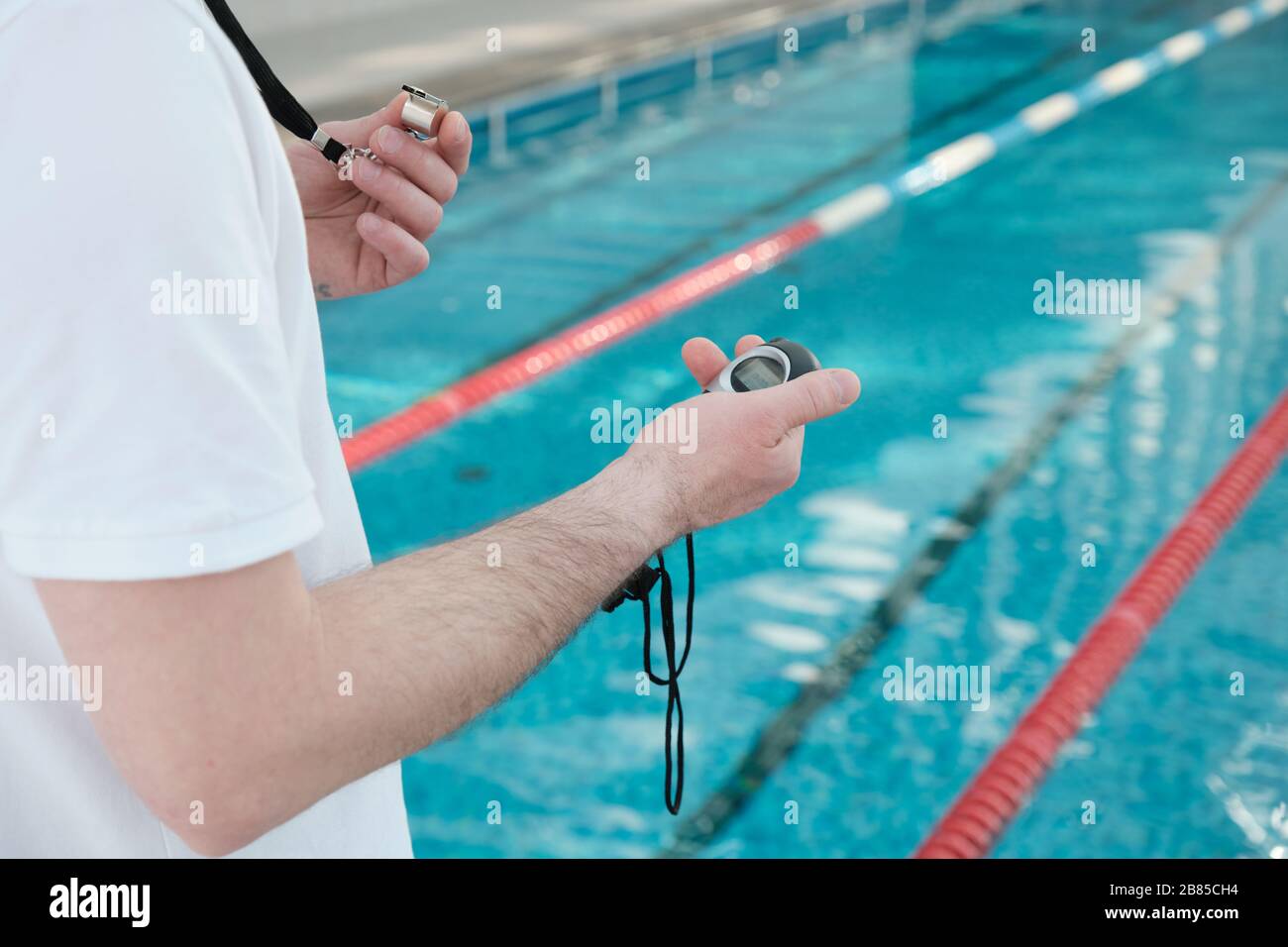 Close-up of unrecognizable coach holding whistle and using stopwatch at ...