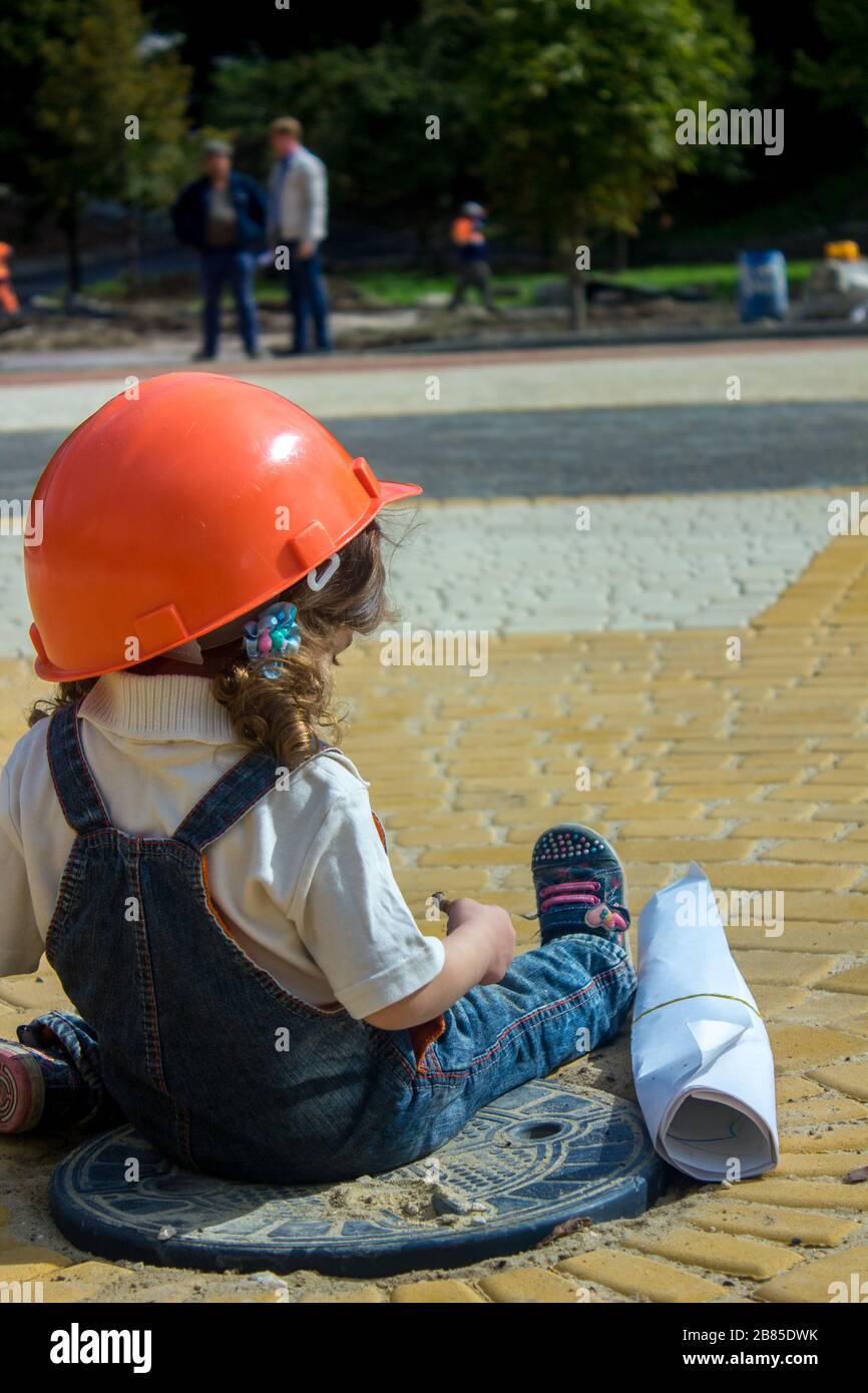 Little baby girl builder with the construction helmet and poster in ...