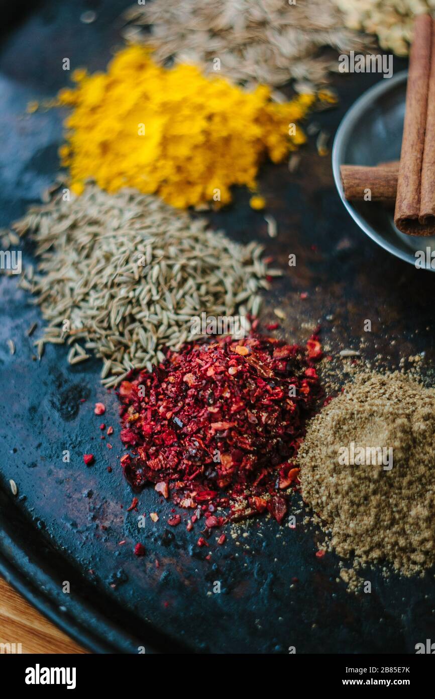 Red sumac spice on black metal plate surrounded by other spices Stock ...