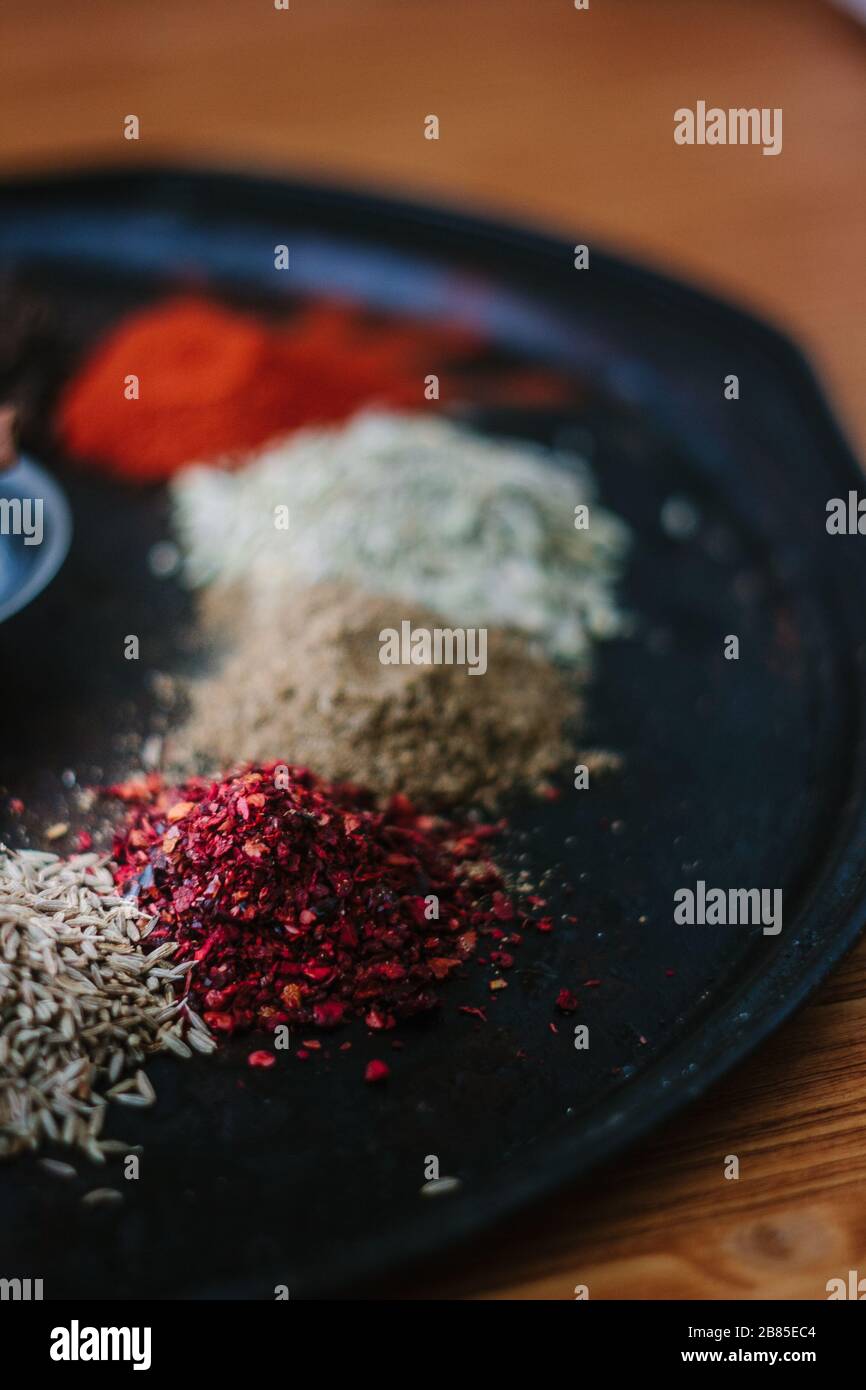 Red sumac spice on black metal plate surrounded by other spices Stock ...