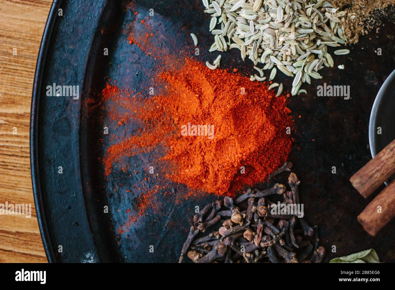 Grounded chili pepper on black rustic surface, surrounded by spices ...