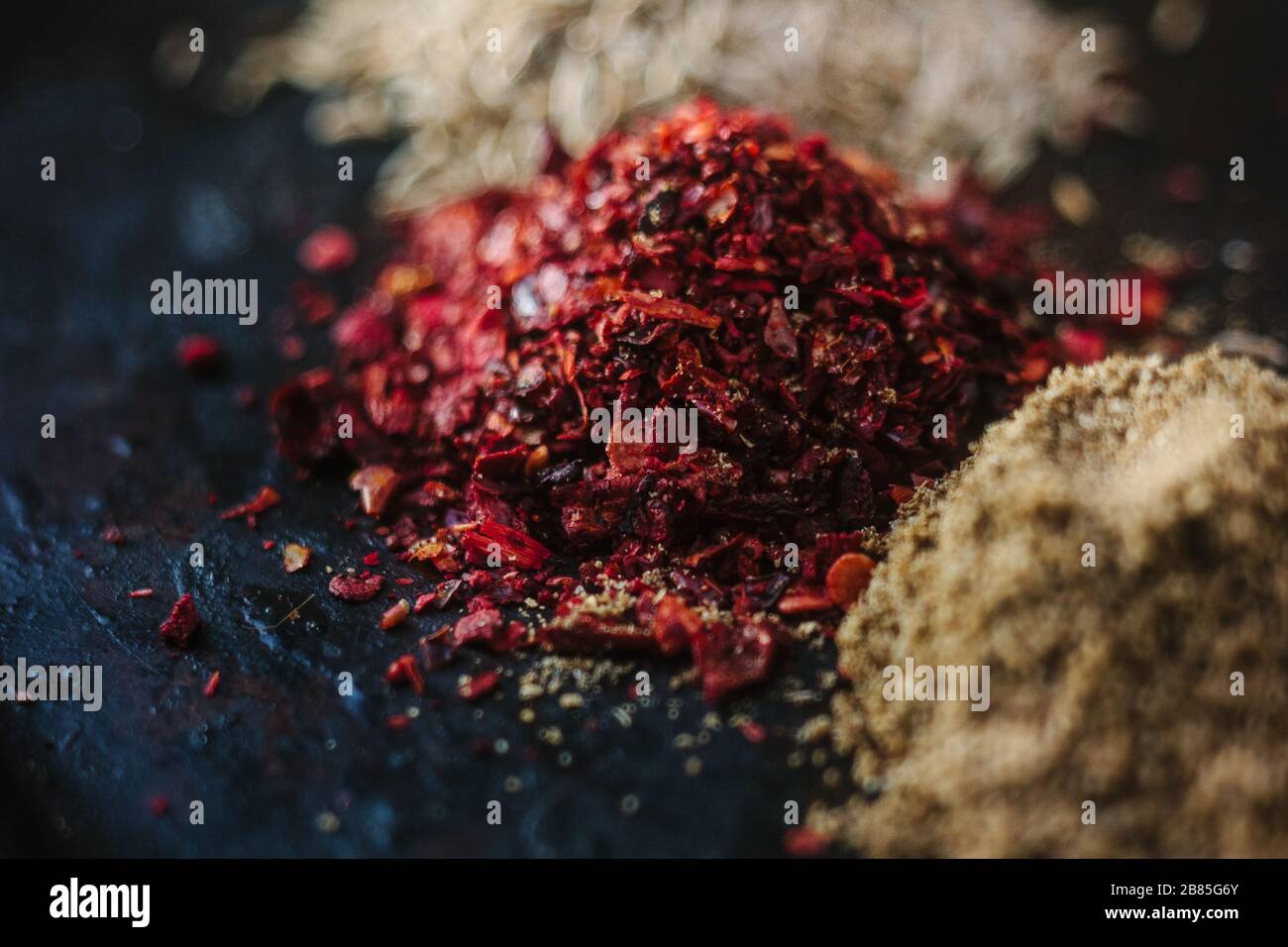 Red sumac spice on black metal plate surrounded by other spices Stock ...