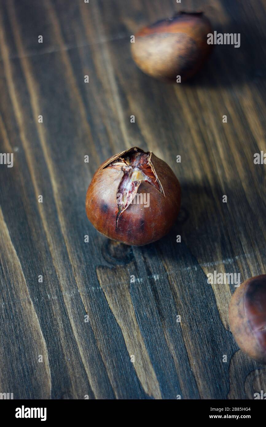 Roated chestnuts on cast-iron pan over wooden surface Stock Photo - Alamy