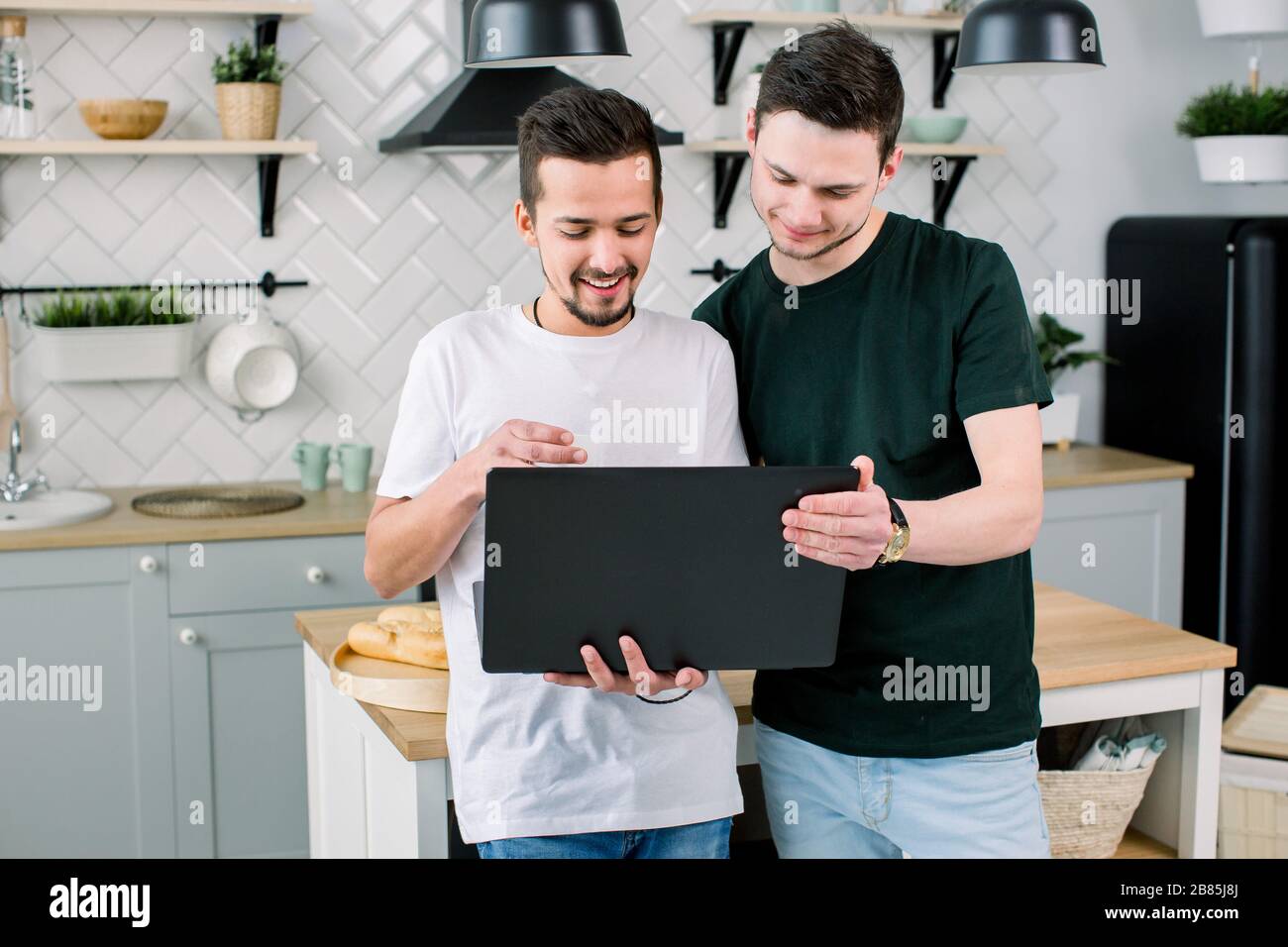 Two happy friends having fun while using laptop together. Happy smiling ...