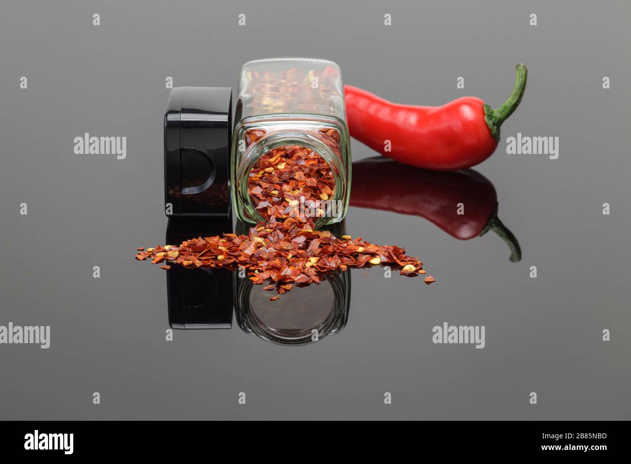 Mild chilli flakes pouring out of glass jar Stock Photo - Alamy