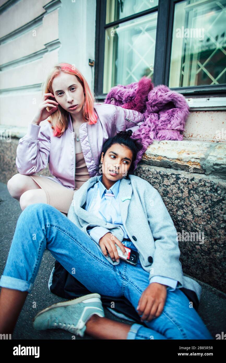 Two teenage girls infront of university building smiling, having fun ...