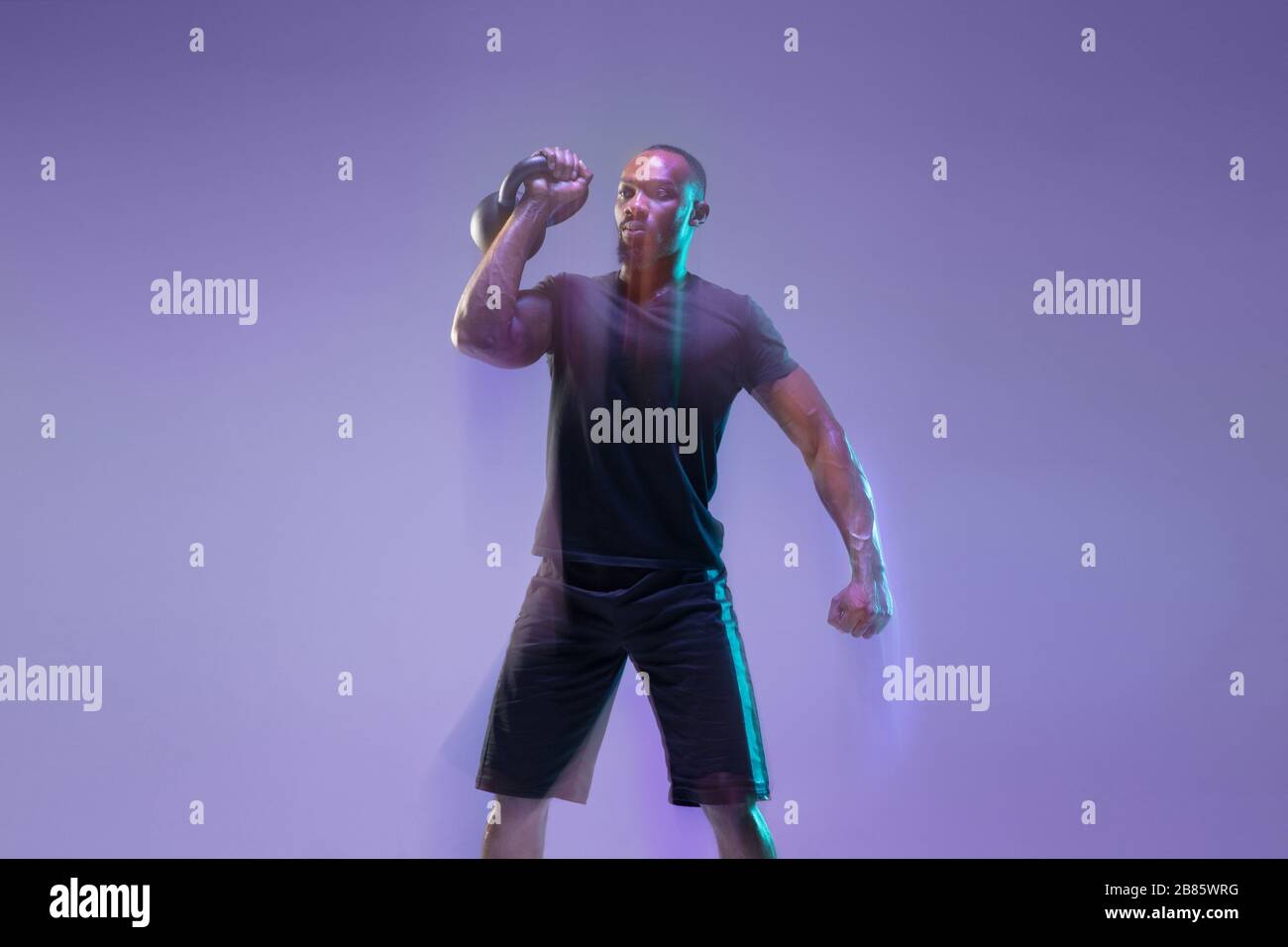 Move. Young african-american bodybuilder training over purple ...
