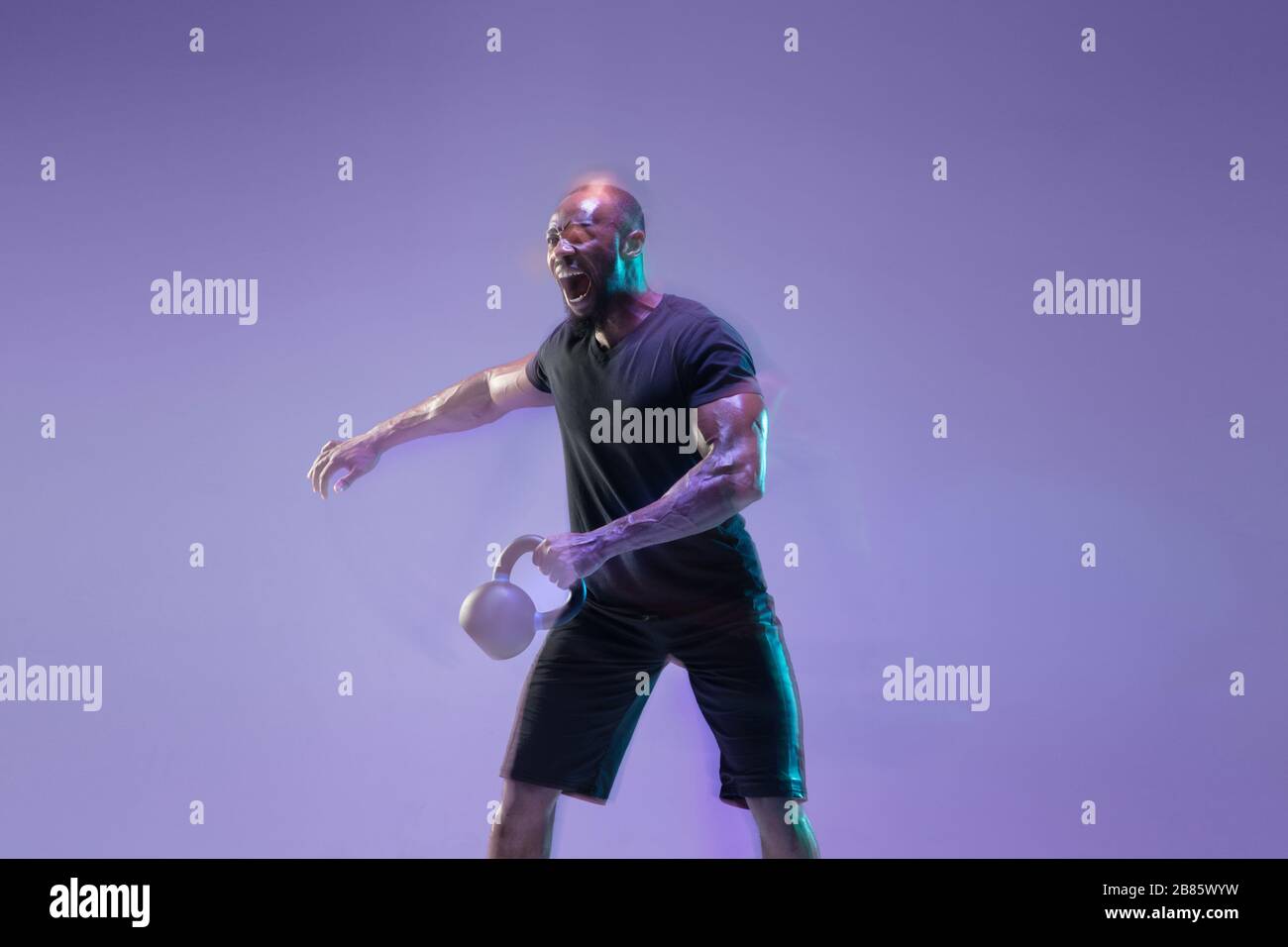 Emotions. Young african-american bodybuilder training over purple ...