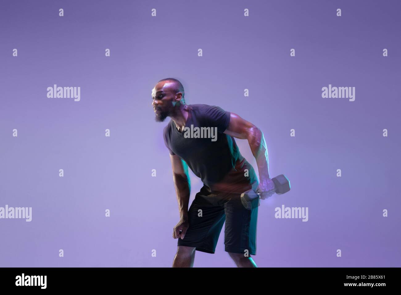Emotions. Young african-american bodybuilder training over purple ...