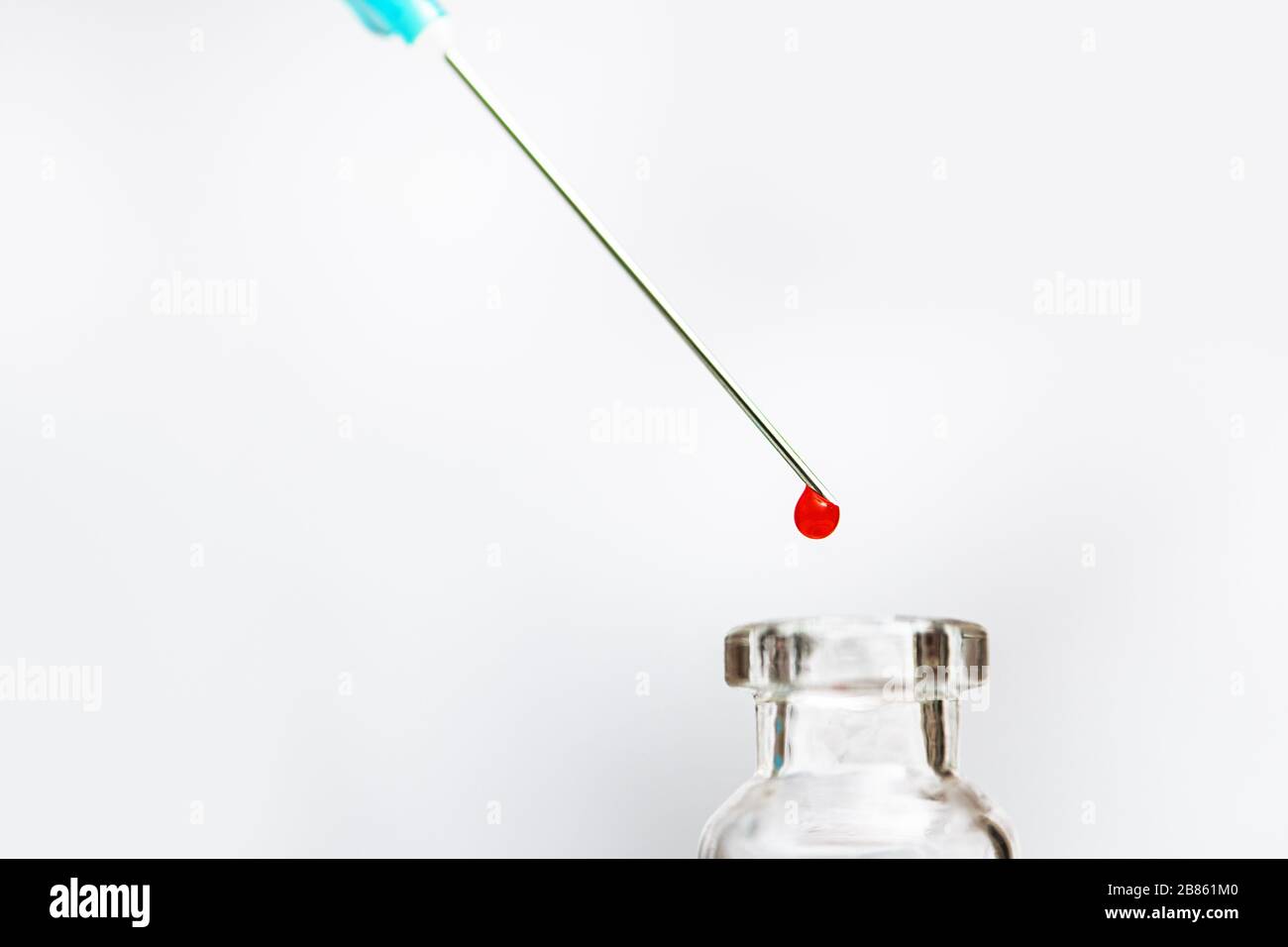 Vial and syringe needle with drop of red fluid Stock Photo - Alamy