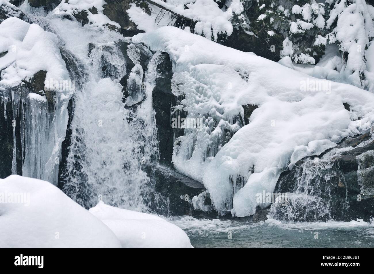 Beautiful snowy waterfall flowing in the mountains. Winter landscape ...