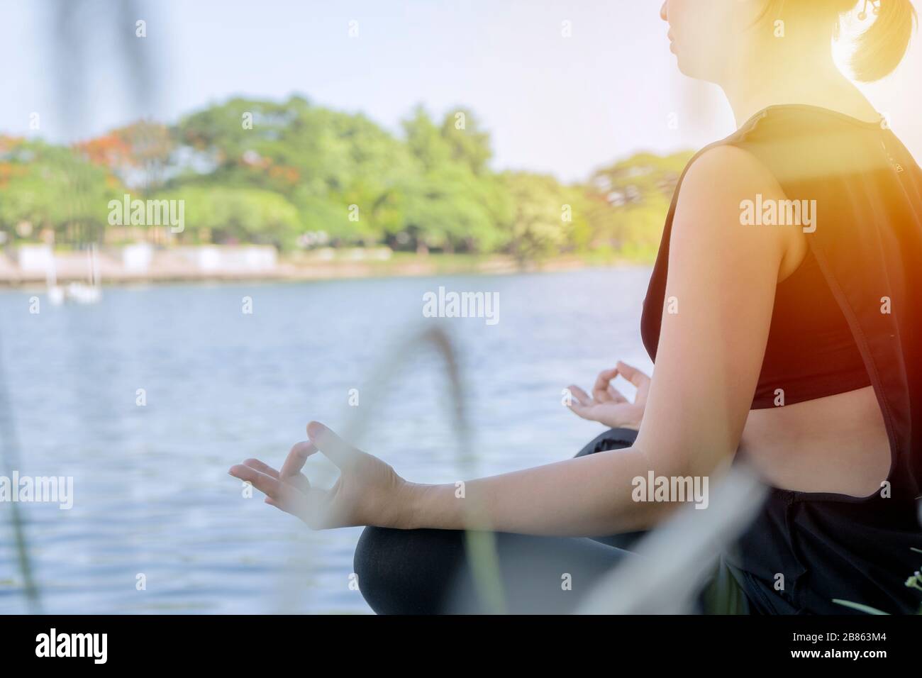 Young attractive smiling woman practicing yoga, sitting in Half Lotus ...