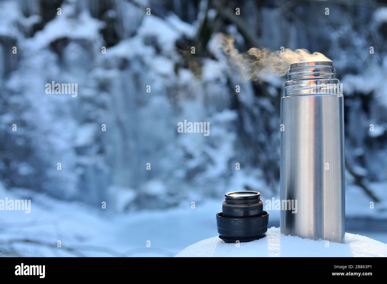 Metal thermos with a hot drink on the background of a winter mountain ...