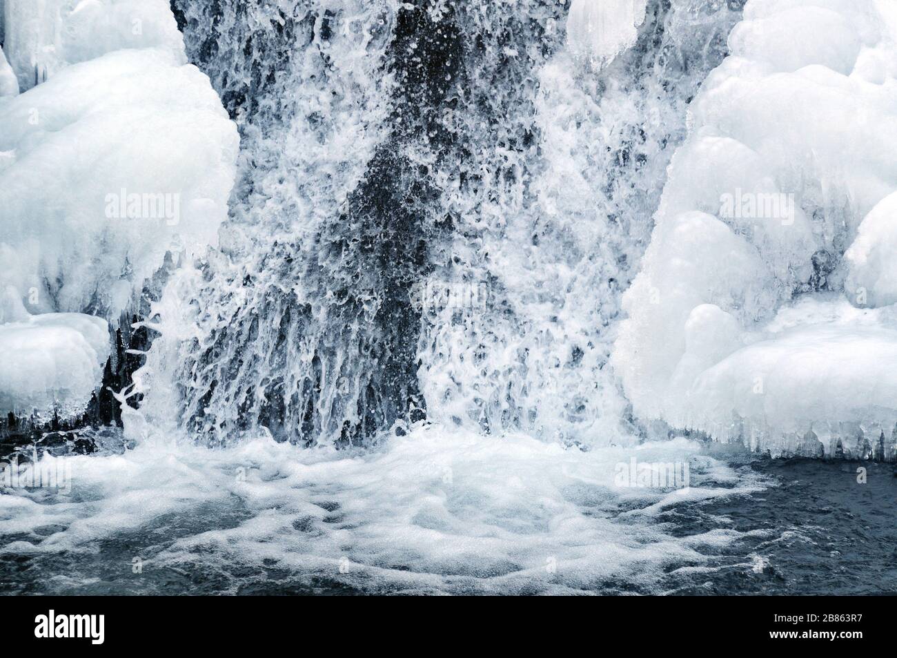 A small active waterfall. Clean mountain stream, snowy winter landscape ...