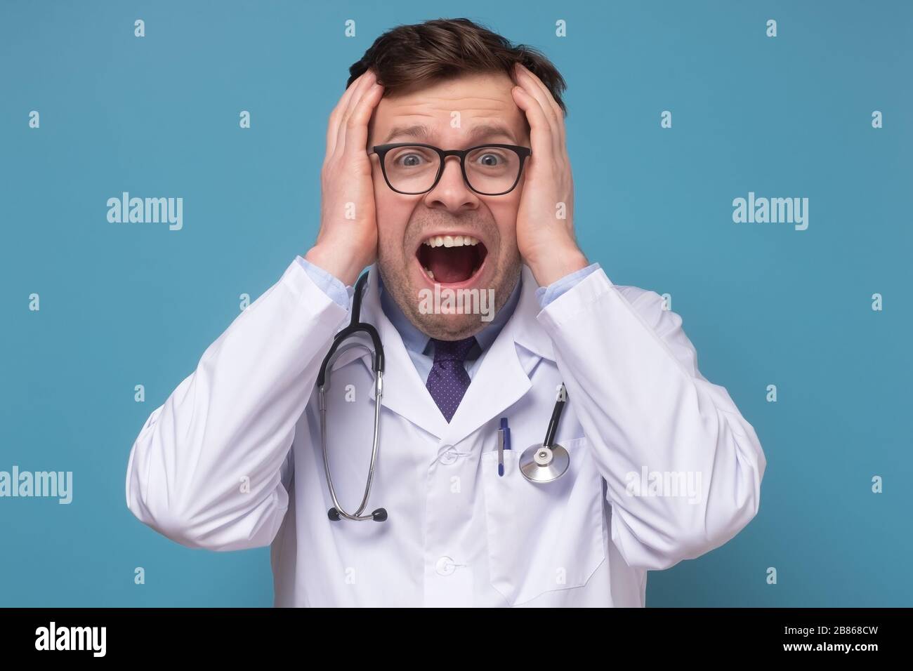 Stressful male doctor screaming in panic, keeps hands on head, finds ...
