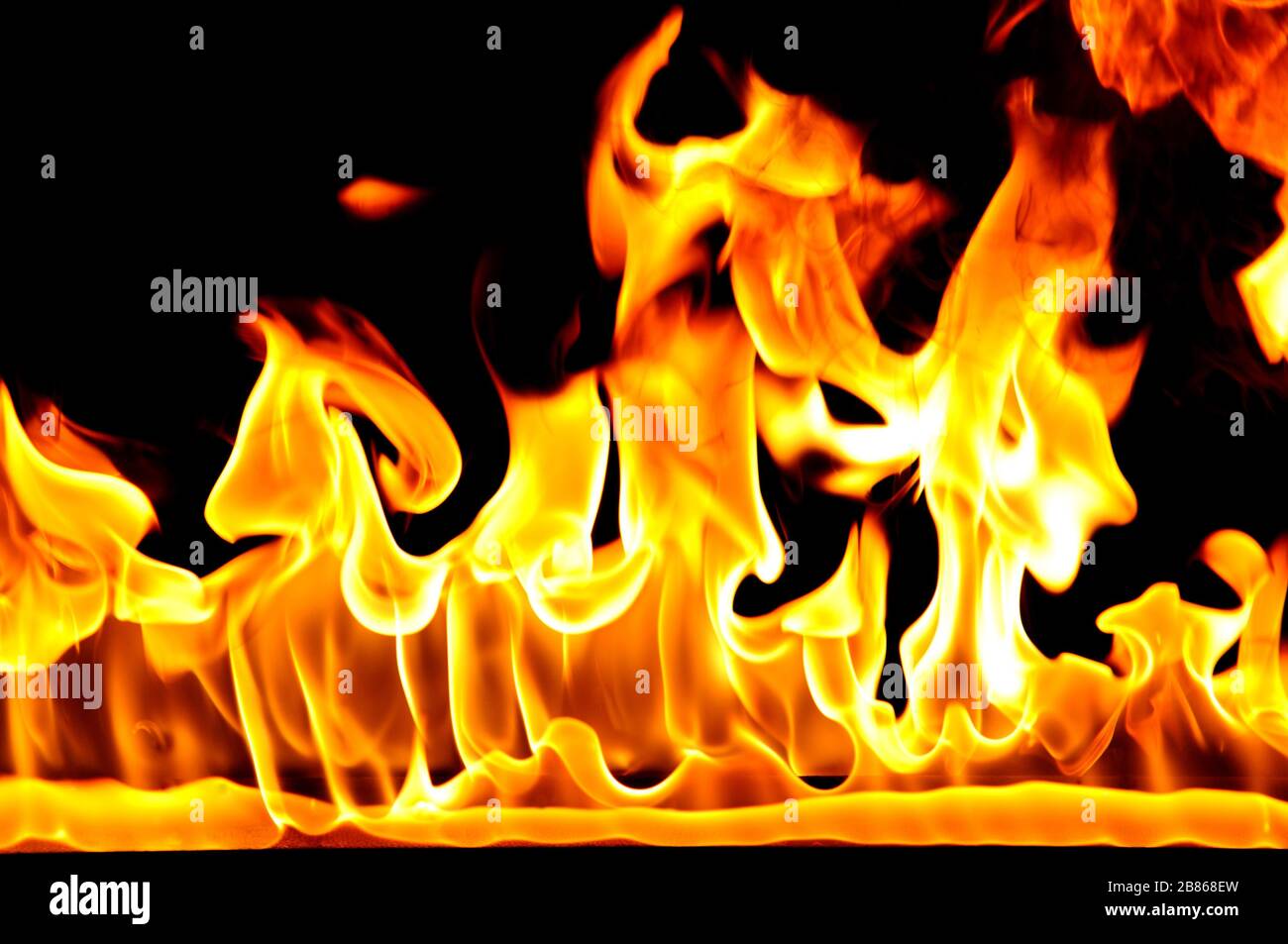 Close-up photo of bright orange yellow flame on a black background ...