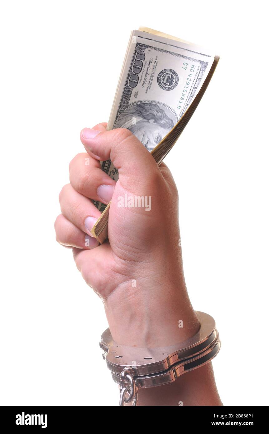 Close-up hand in handcuffs tightly squeezes a pack of one hundred ...