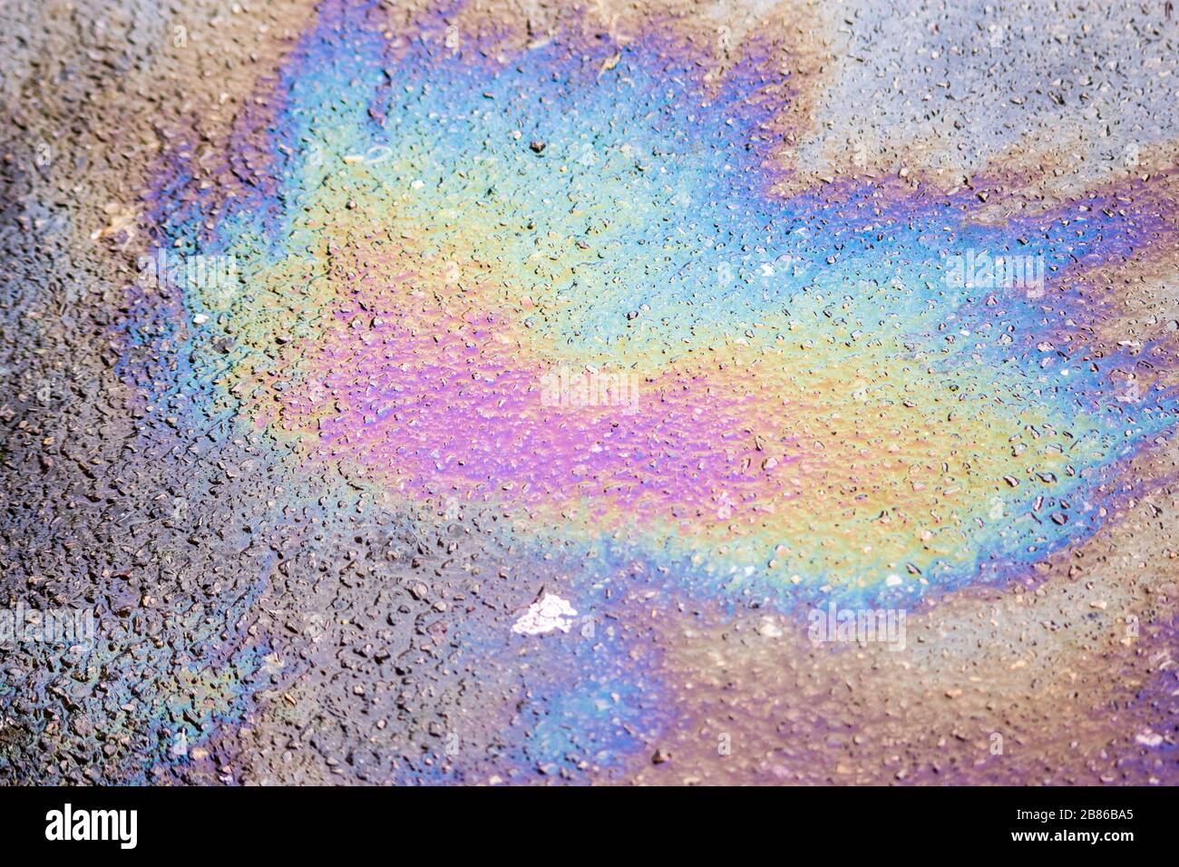 A patch of spilt oil has mixed with rain to show iridescent rainbow ...