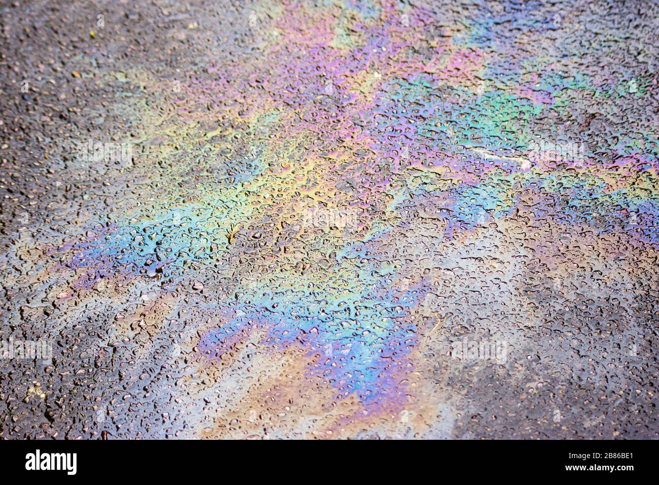 Leaked oil spreading in iridescent patterns across the a road surface ...
