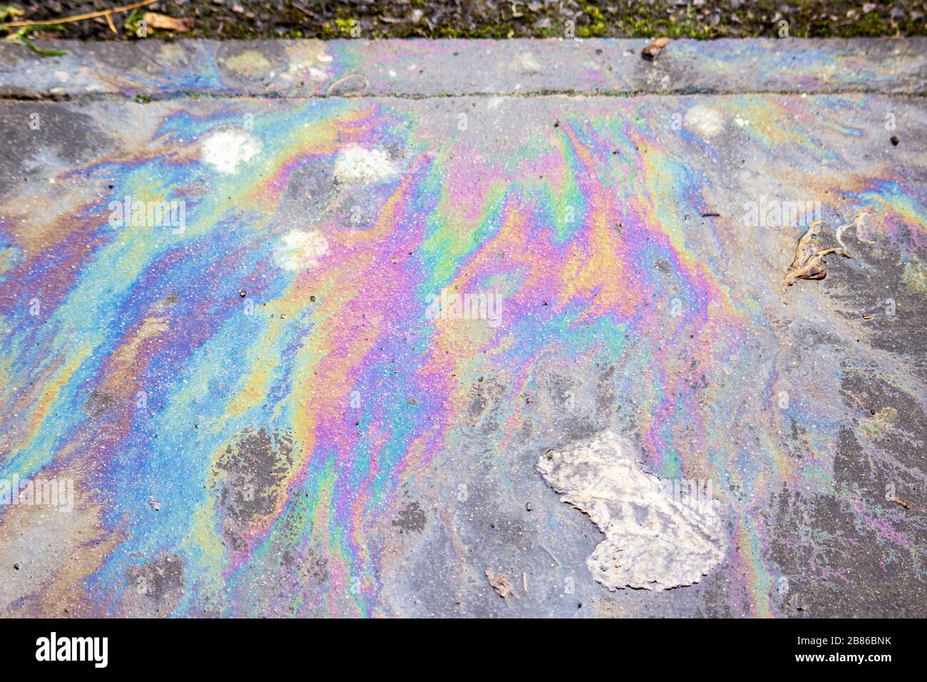 The iridescent rainbow colours of spilt oil n a dirty path Stock Photo ...