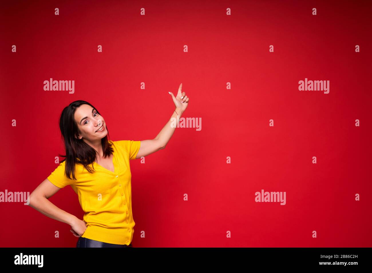 Happy successful young woman with raised arm pointing her finger to the ...
