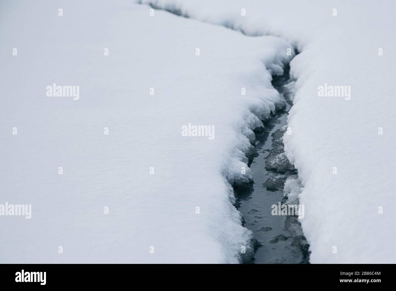 A crack formed on the white snow. Water is visible in the crack Stock ...