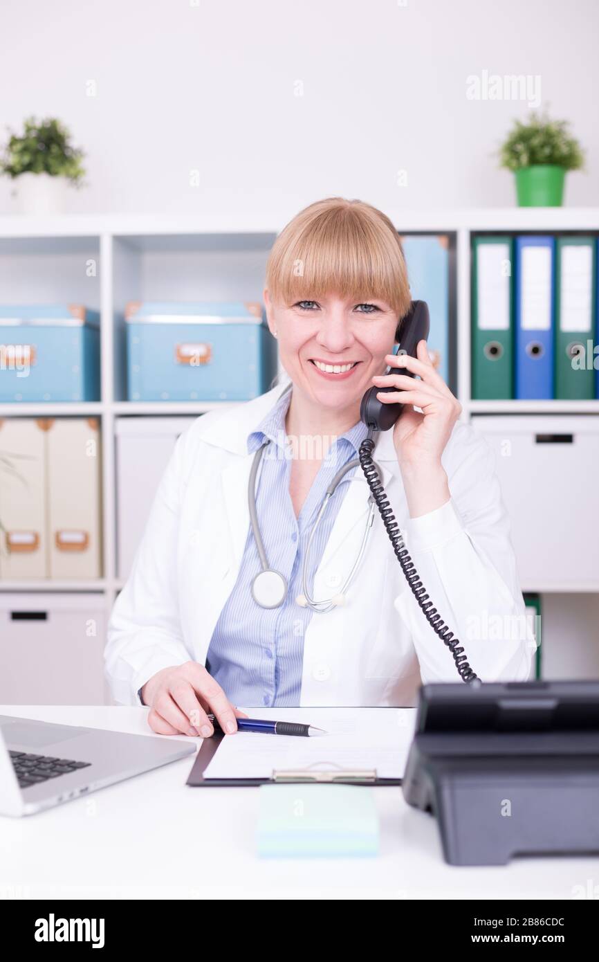 Female doctor giving advice at medical telephone hotline at home office ...