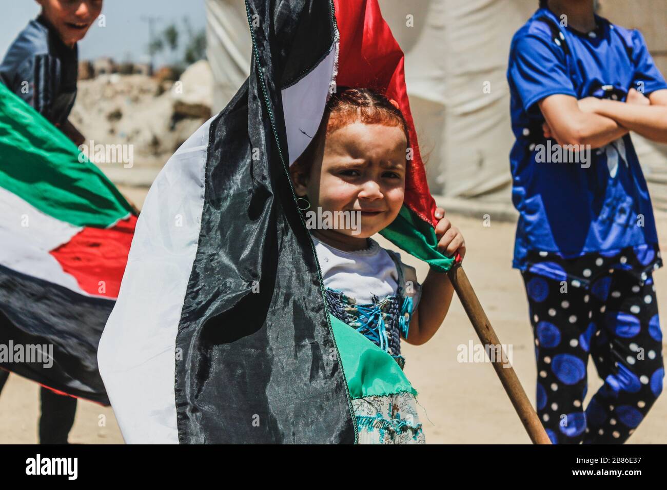 small kid hold palestinian flag and raise the victory sign during the ...