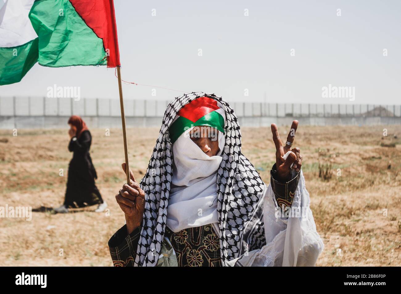 Old lady hold palestinian flag and raise the victory sign during the ...