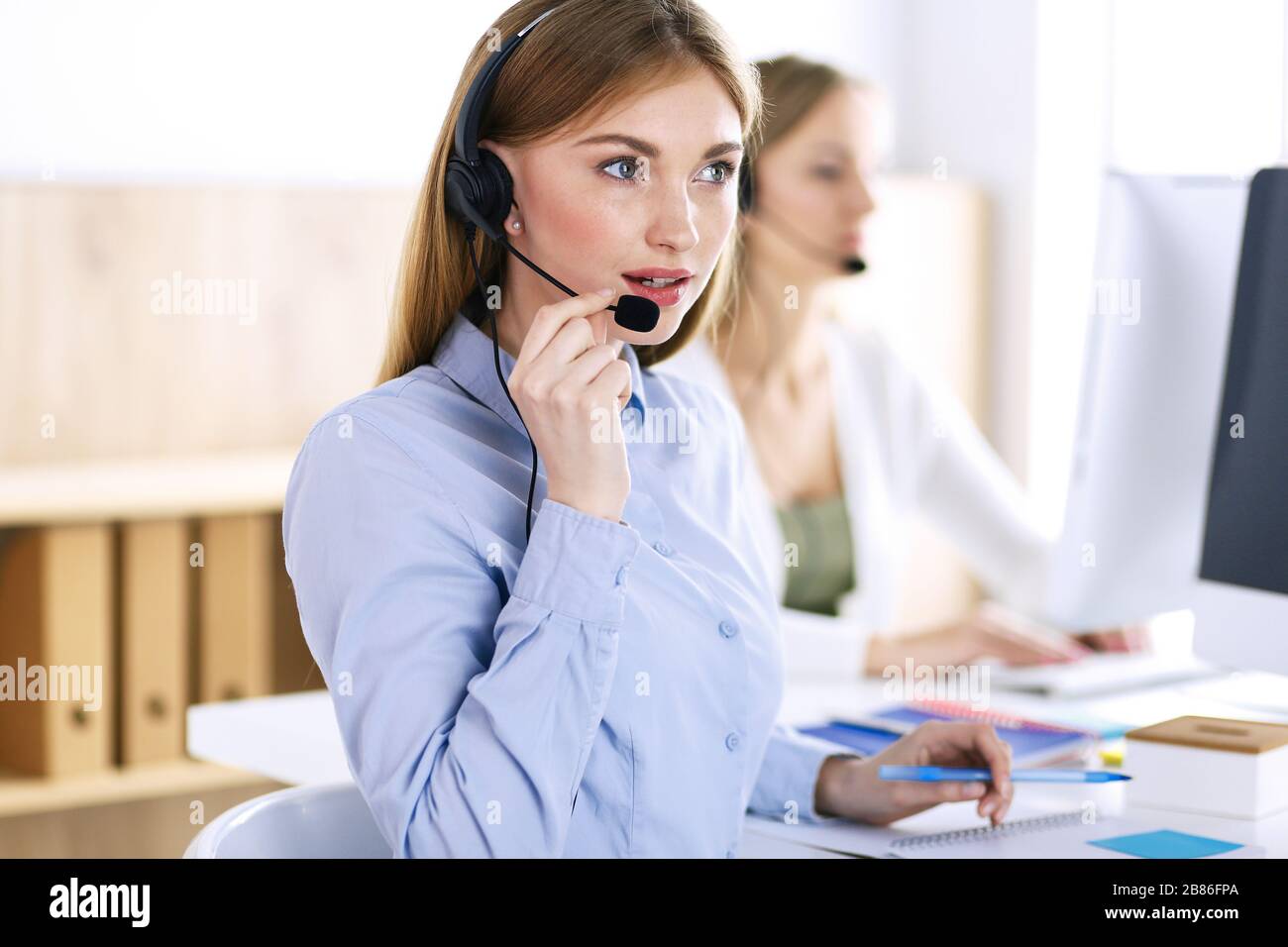 Portrait of call center operator at work. Group of people in a headset ...