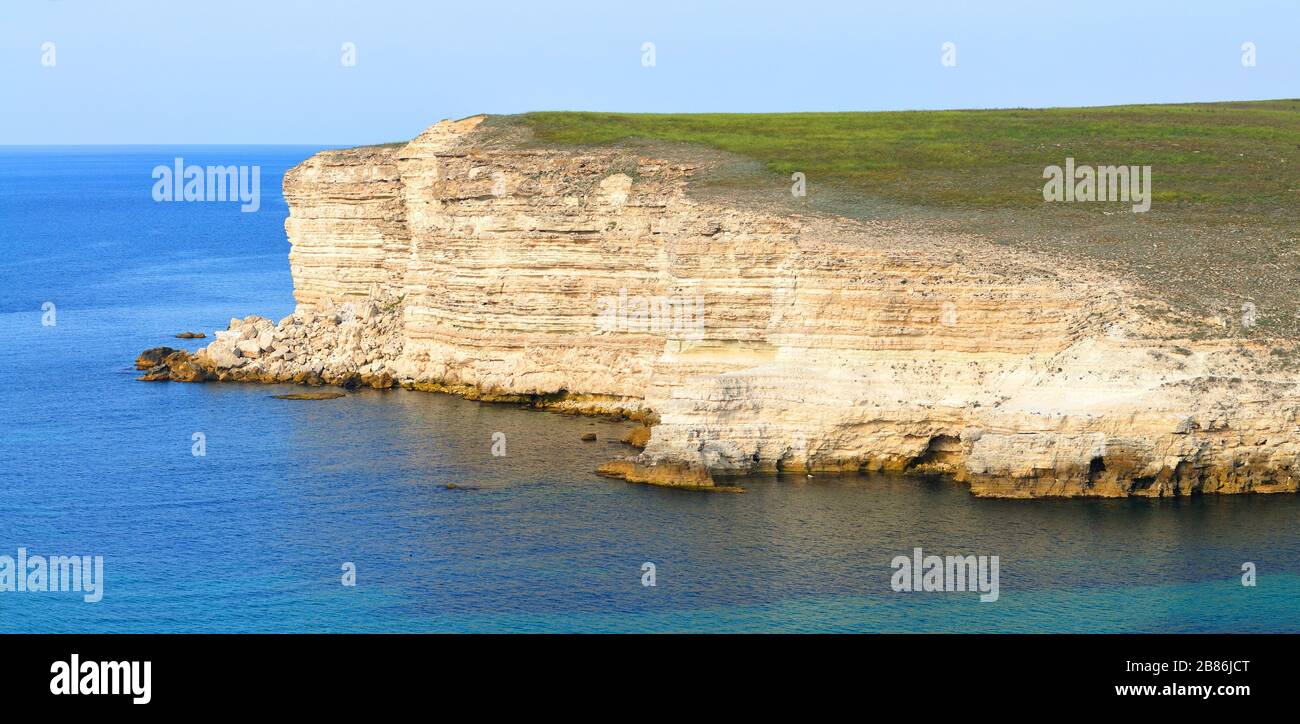 Black sea rocks at coastline with clear blue waters and blue sky ...