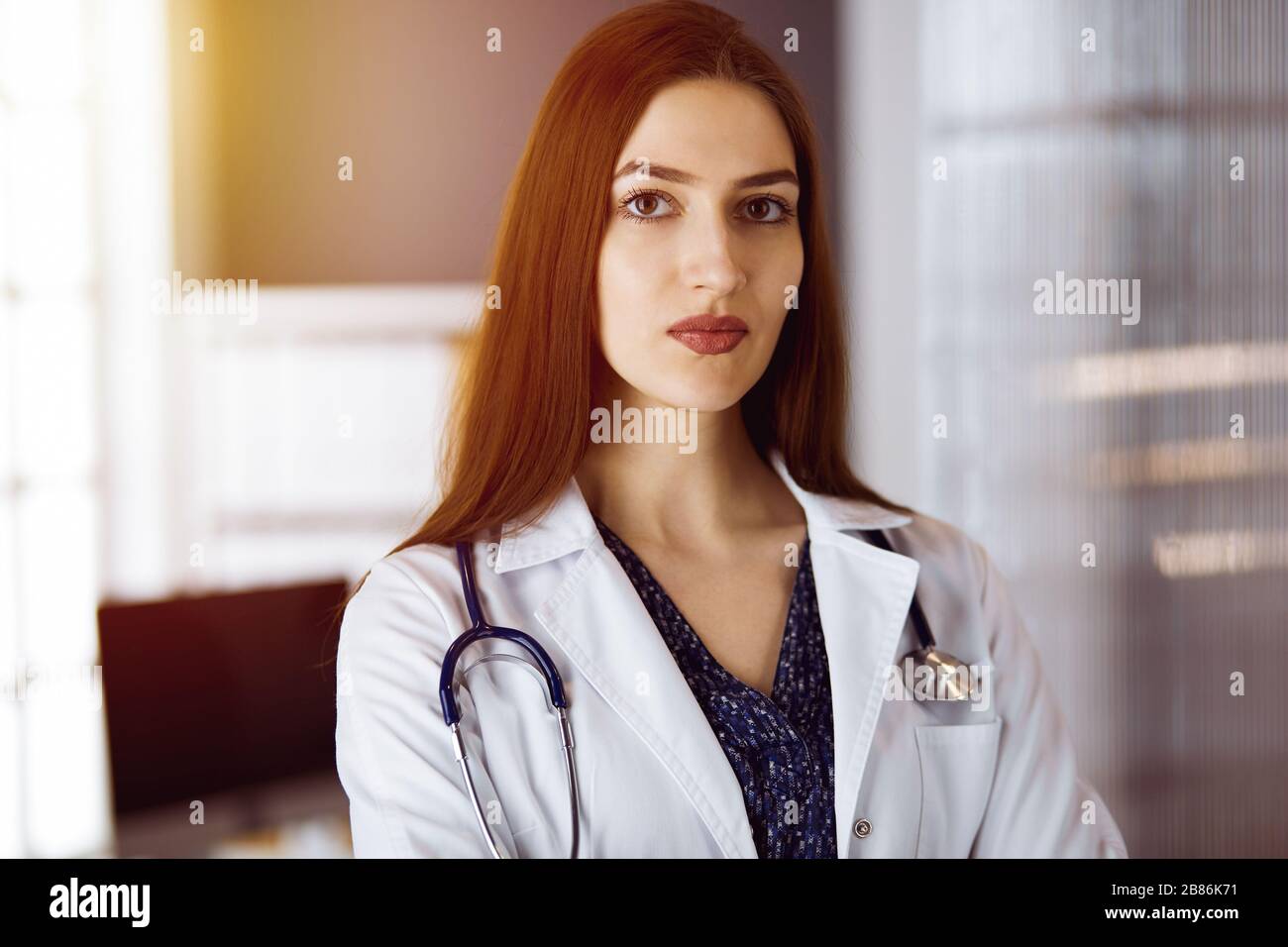 Cheerful Smiling Female Doctor Standing With Arms Crossed In Clinic