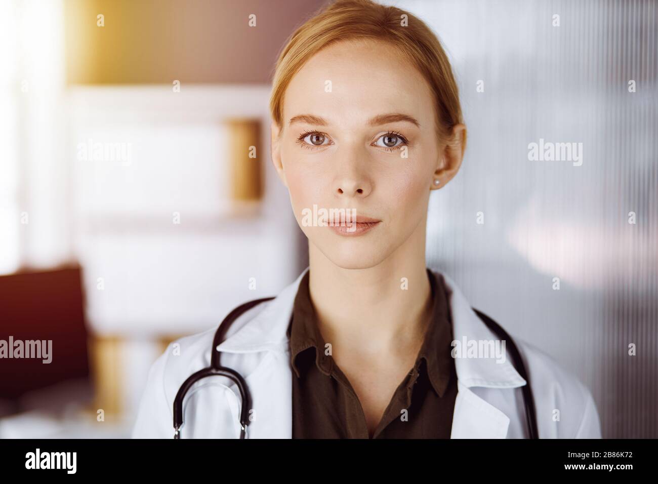 Cheerful smiling female doctor standing with arms crossed in clinic ...