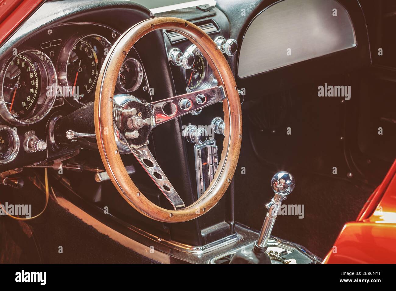 Retro styled image of the dashboard of a classic car with wooden steer ...