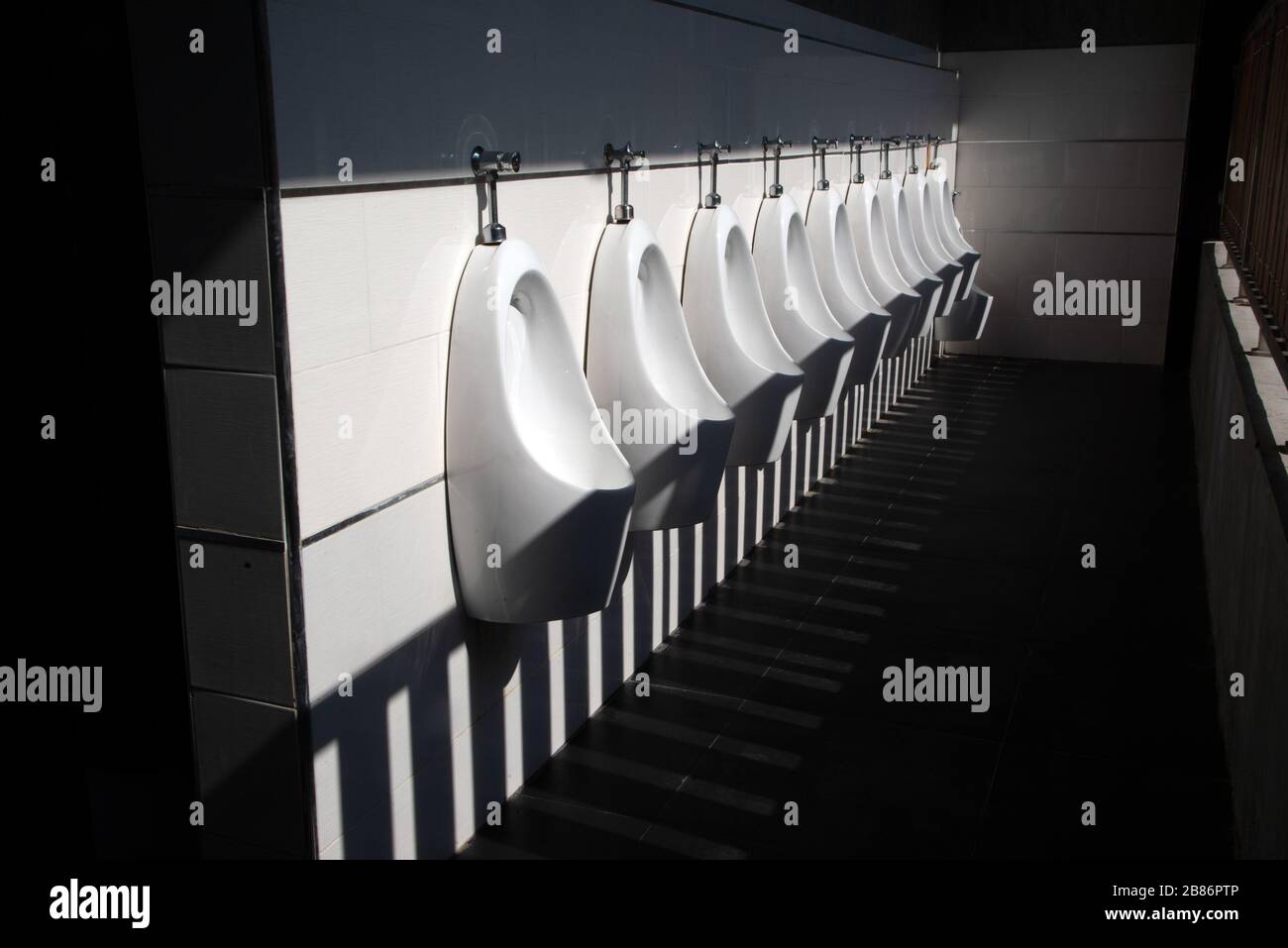 Art light and shadow of men's restroom with white porcelain urinals in ...