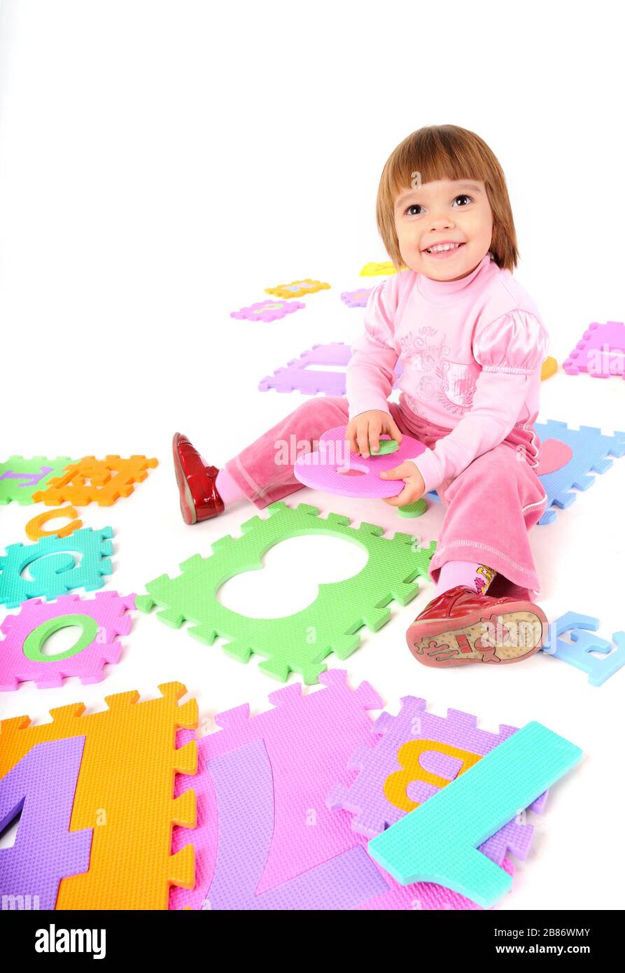 Small smiling girl in pink clothing sitting, learning numbers and ...