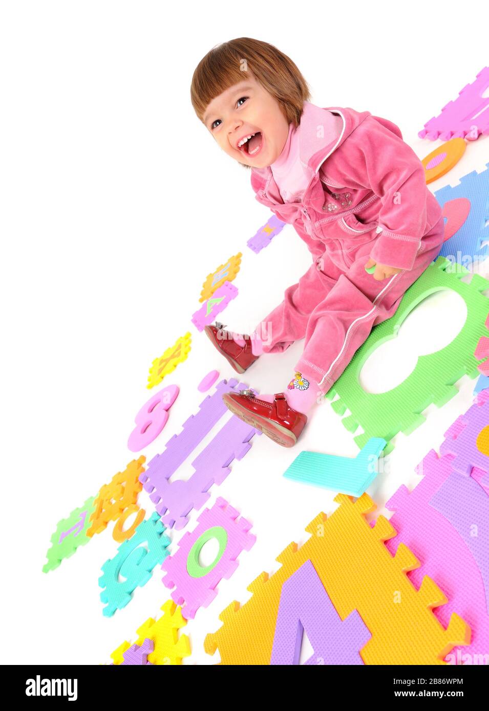 Small smiling girl in pink clothing sitting, learning numbers and ...