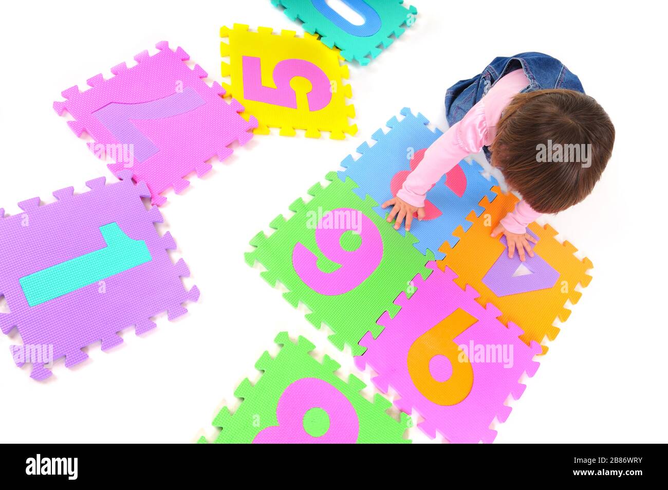 Small smiling girl in pink clothing sitting, learning numbers and ...