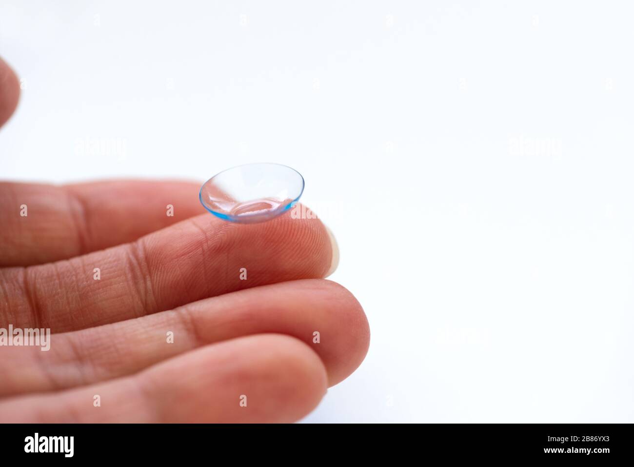 Female finger with contact lens on white background. Soft focus. Macro ...