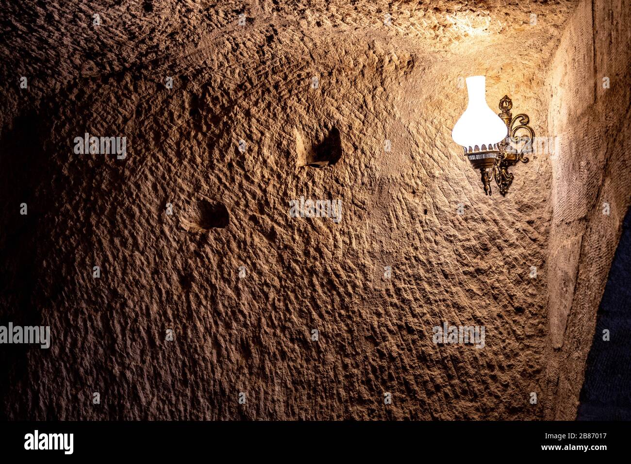 Ancient rough wall in cave with light from lamp in darkness. Antique ...