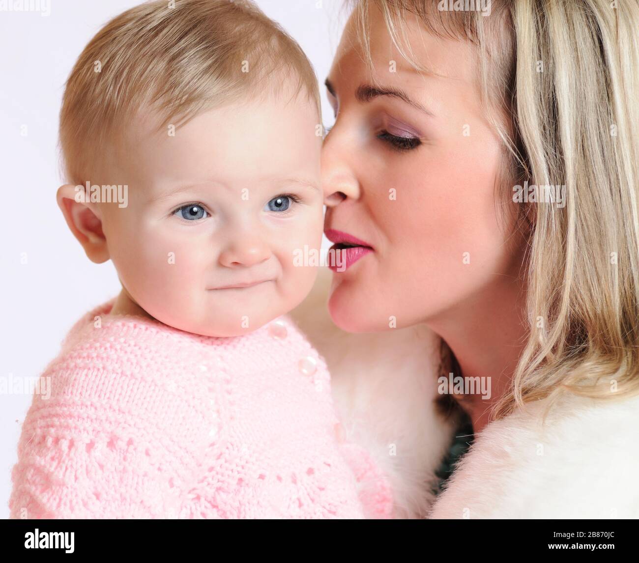 Close-up of a woman snuggling nose to temple of a child. Baby with big ...