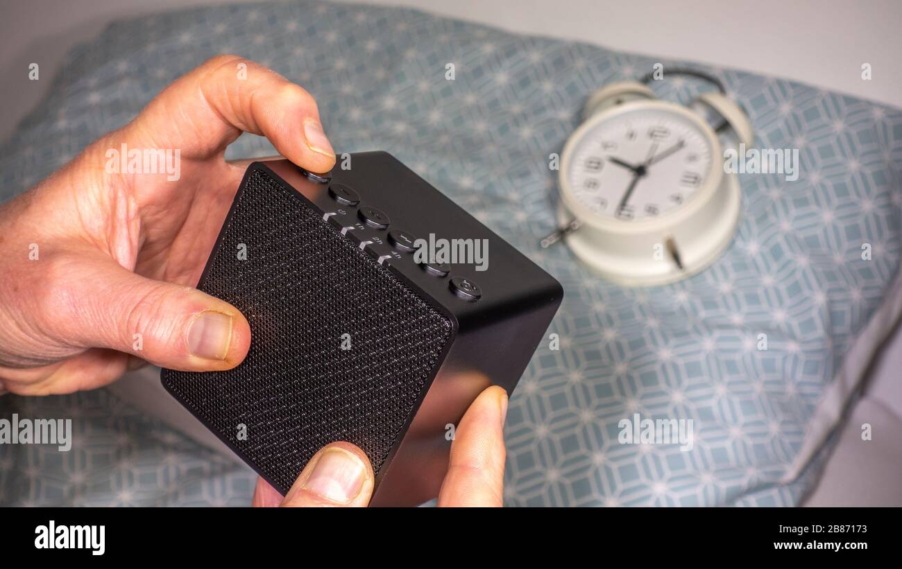 Man’s finger pressing the button to turn on a compact, modern, white ...