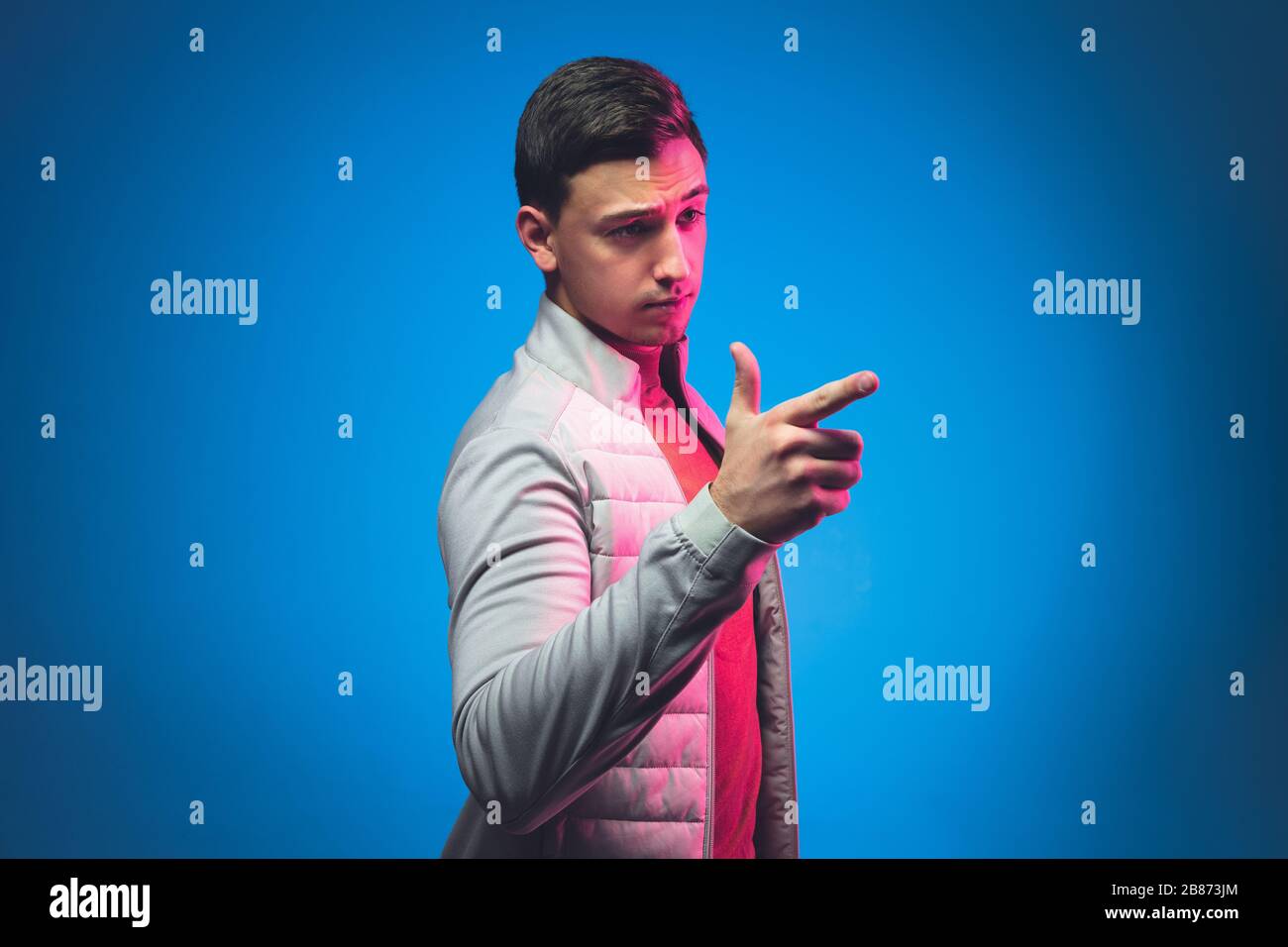 Pointing, choosing. Caucasian man's portrait isolated on blue studio ...