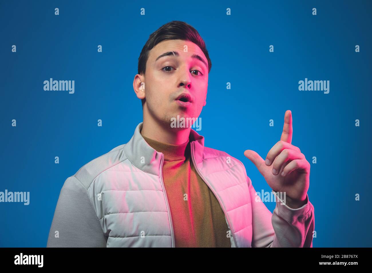 Pointing up. Caucasian man's portrait isolated on blue studio ...