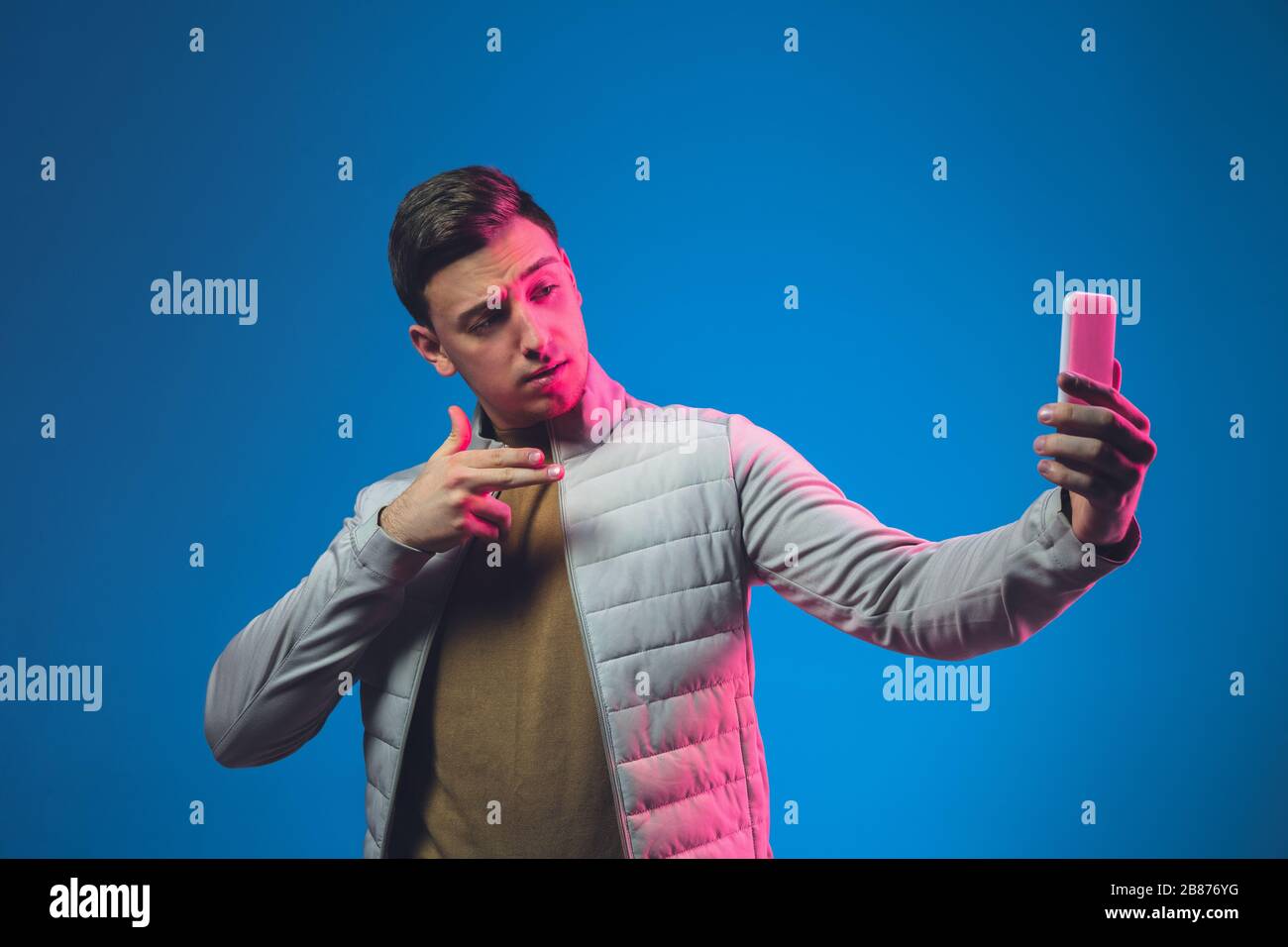 Taking selfie, vlog. Caucasian man's portrait isolated on blue studio ...