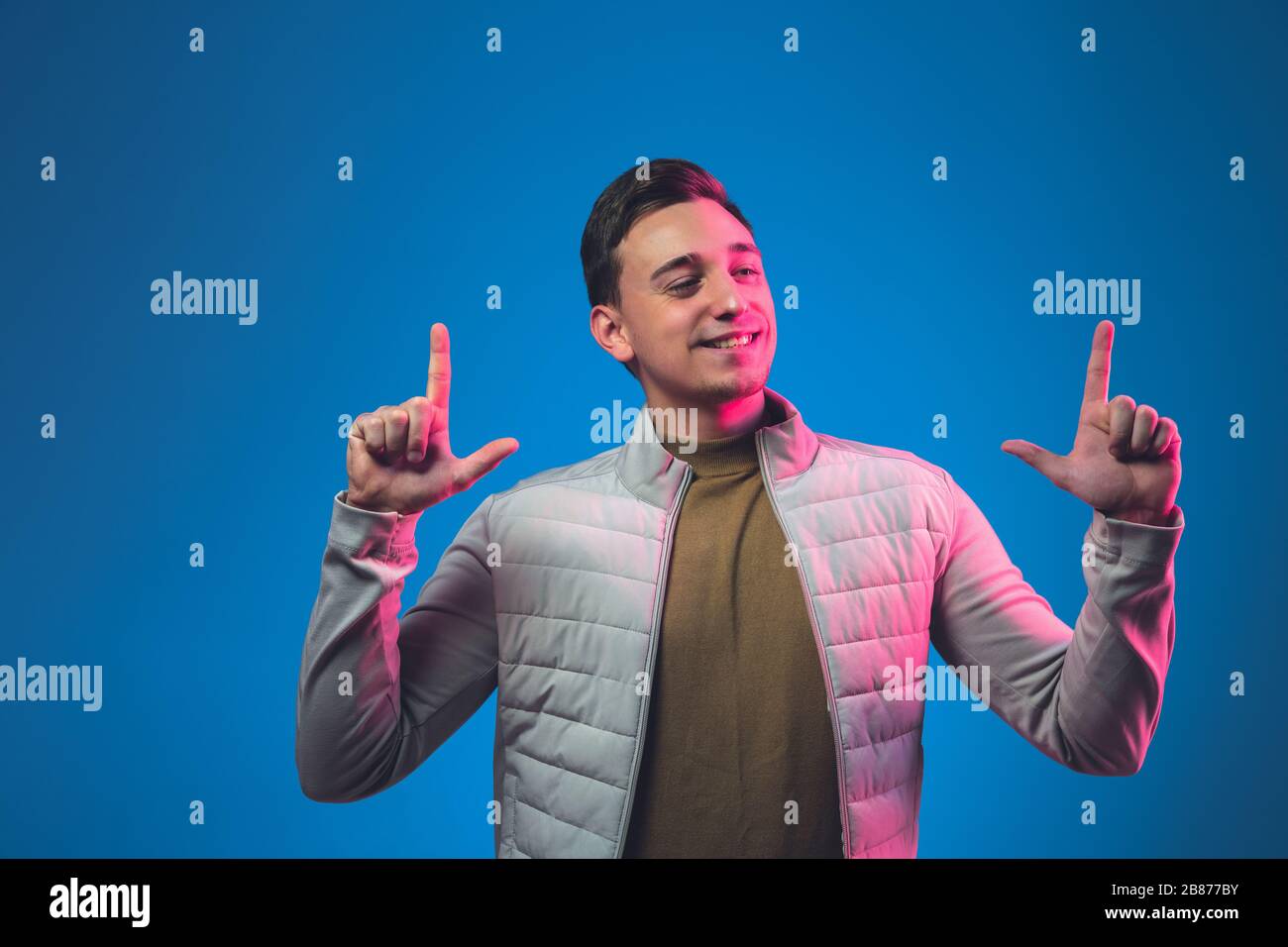 Pointing up. Caucasian man's portrait isolated on blue studio ...
