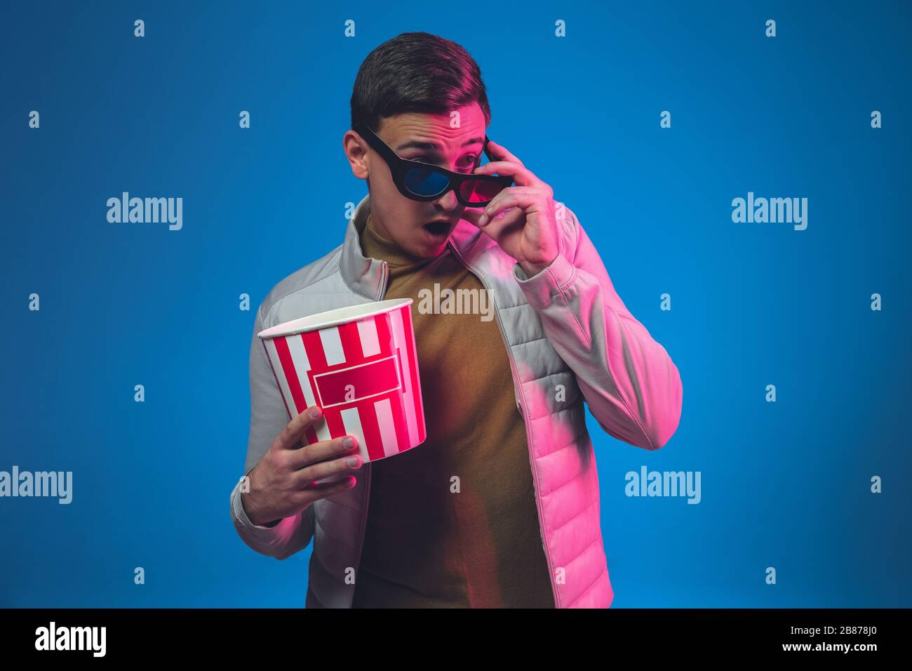 Shocked in 3D eyewear and with popcorn. Caucasian man's portrait ...
