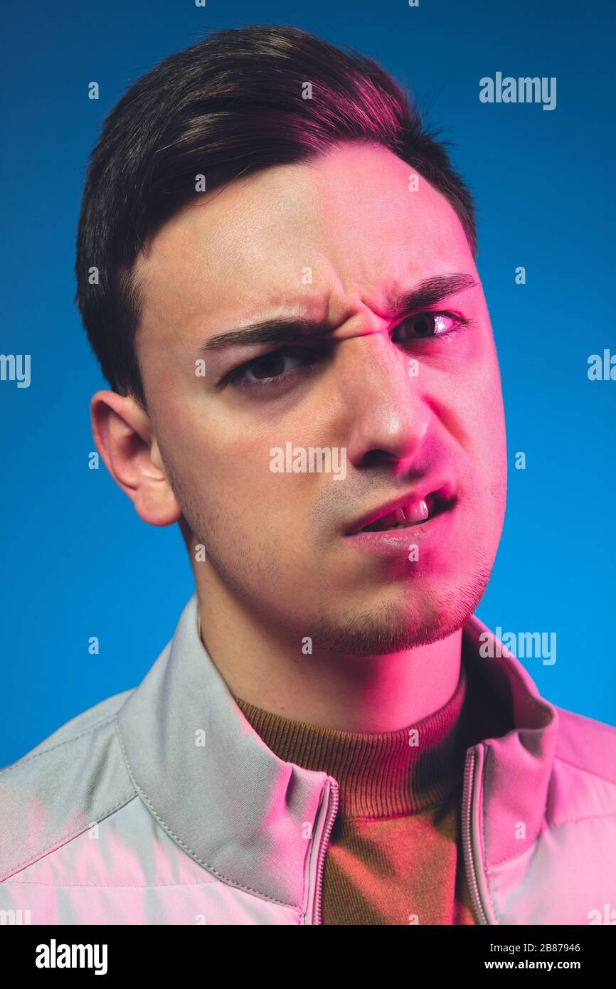 Angry, looking on. Close up caucasian man's portrait isolated on blue ...