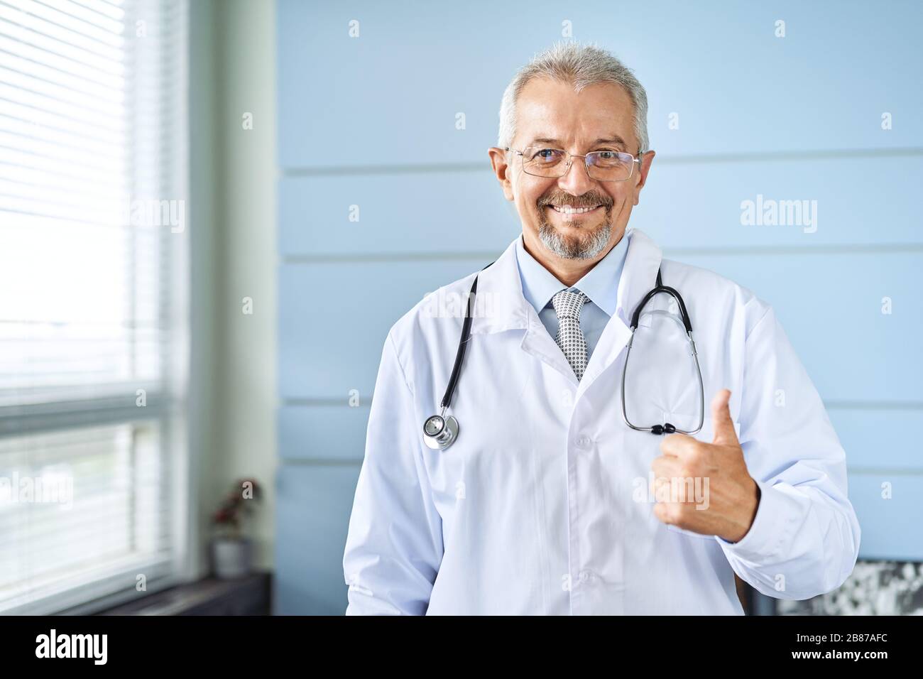 Smiling medical senior doctor with a stethoscope. On a blue background ...